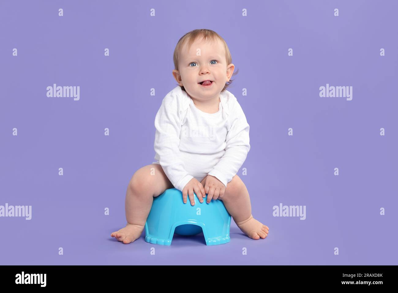 Little child sitting on baby potty against violet background Stock ...