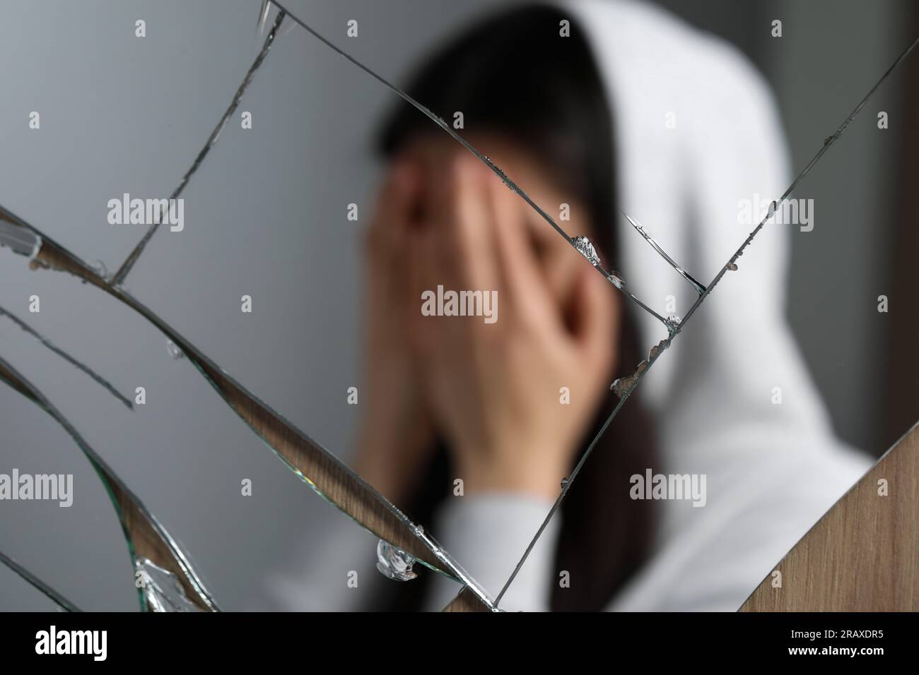 Woman covering face with hands near broken mirror. Mental problems ...