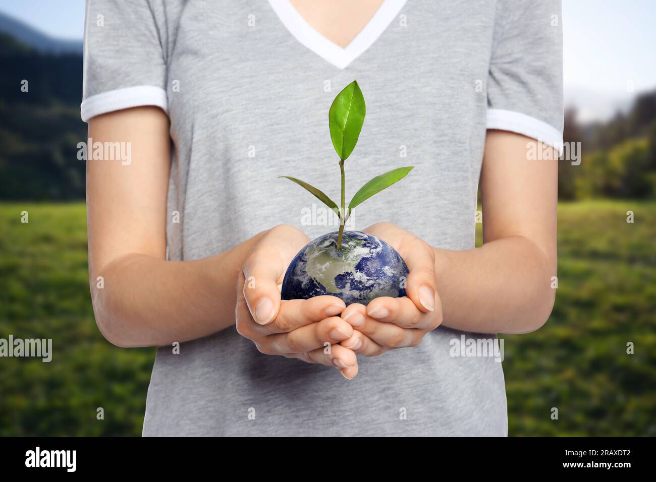 Make Earth green. Woman holding globe with seedling outdoors, closeup ...