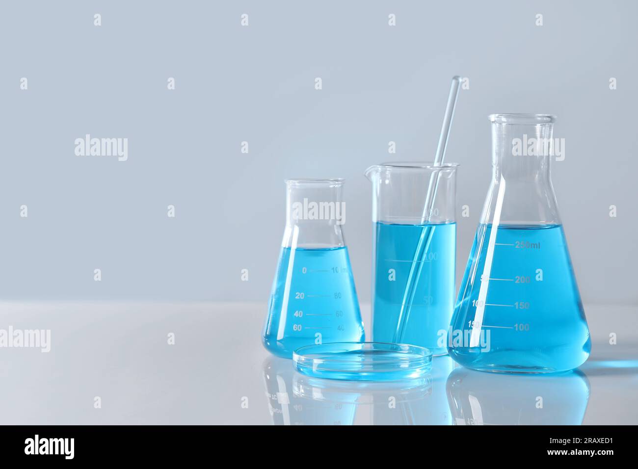 Different laboratory glassware with light blue liquid on table, space ...