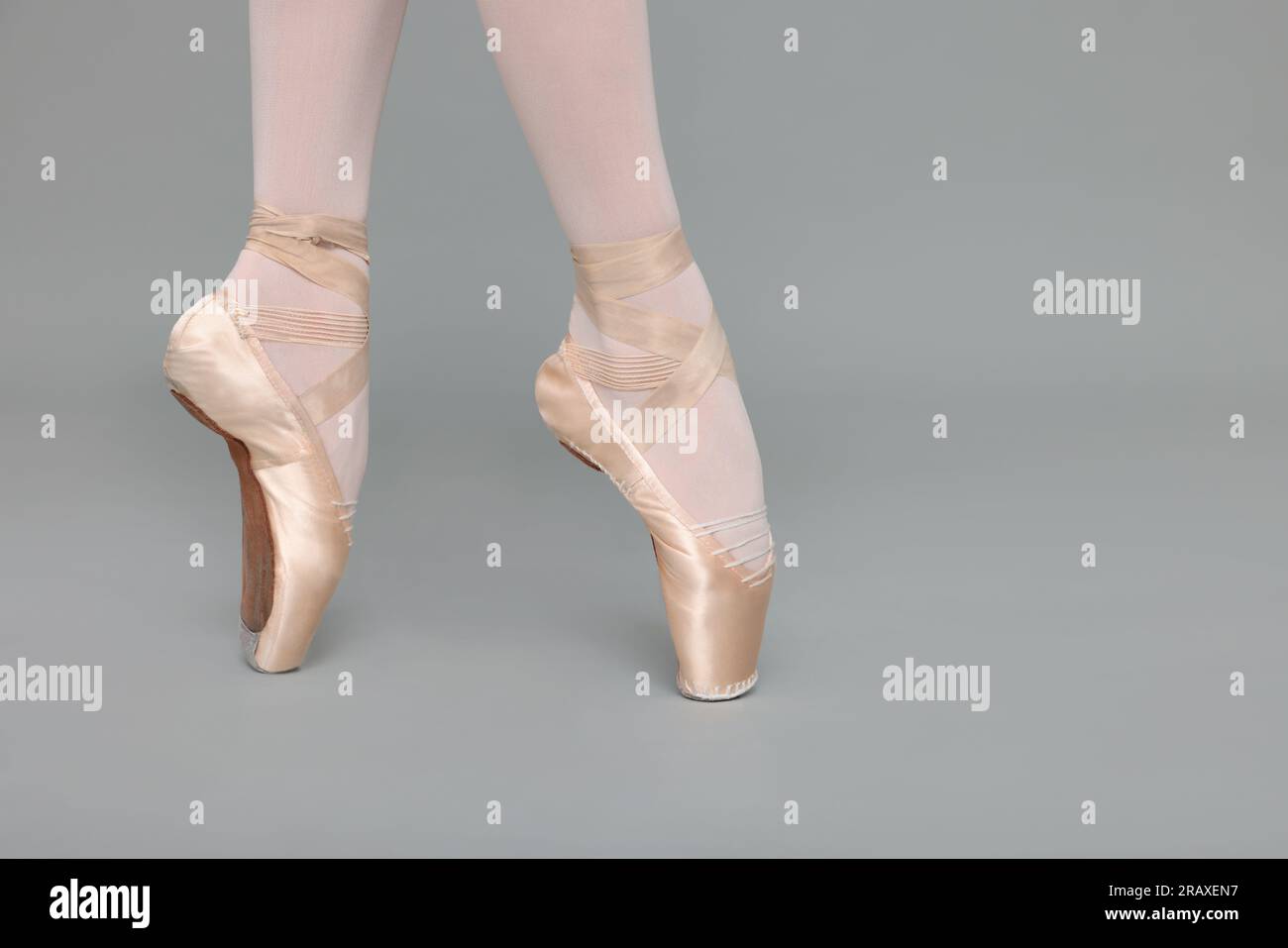Young ballerina in pointe shoes practicing dance moves on grey background, closeup Stock Photo ...