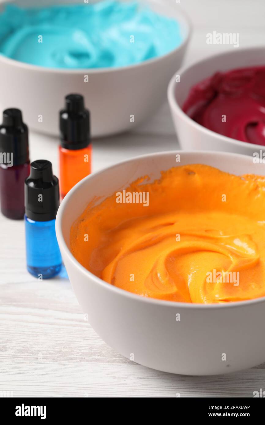 Bowls of different cream with food coloring and bottles of bright ...