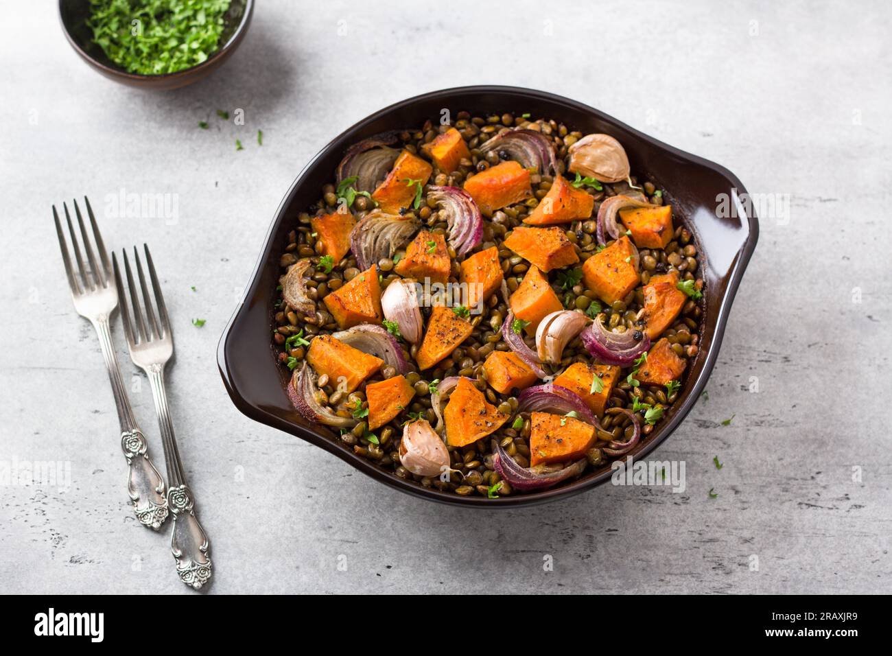 Baked lentils with pumpkin and onions in ceramic mold on a gray ...