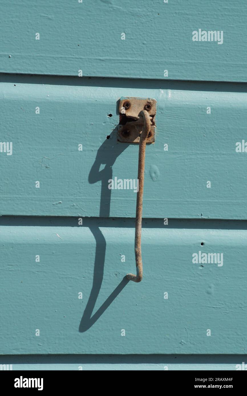 A cabin hook casting a shadow on the outside wall of a light blue beach ...