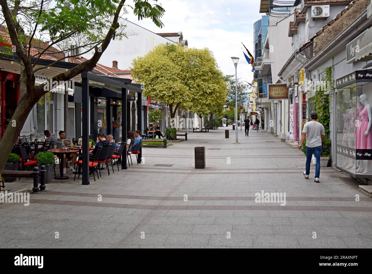 People shoppin and people relaxing outdoors at a bar in the street in ...