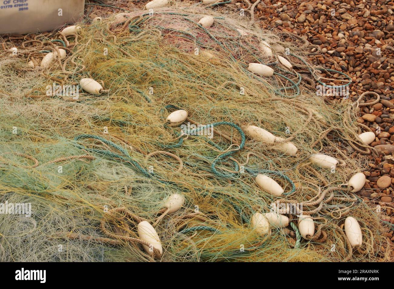 Pile of very fine transparent commercial trawler fishing net and floats ...