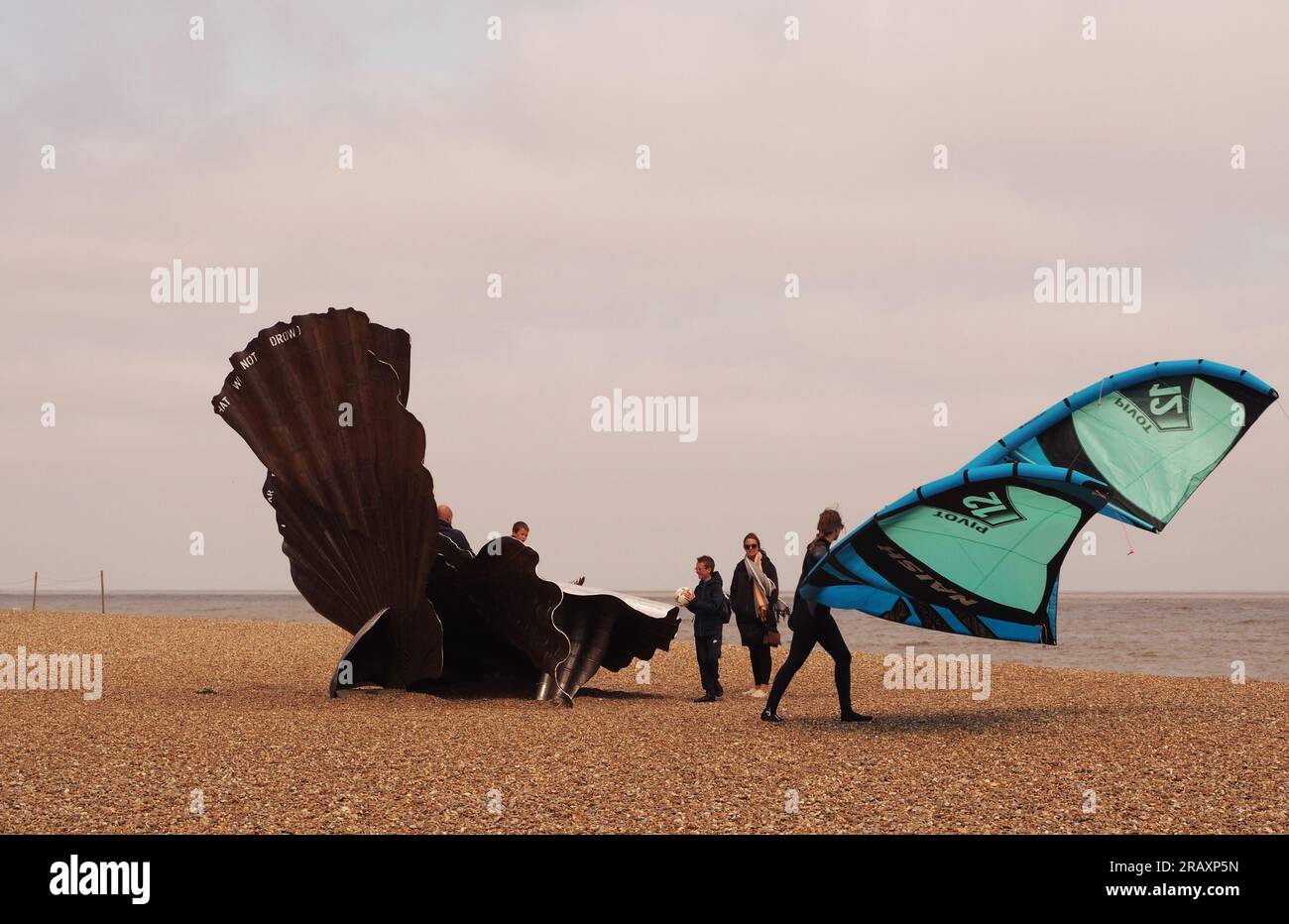 A female windsurfer on the shingle beach at Aldeburgh, Suffolk. UK with ...
