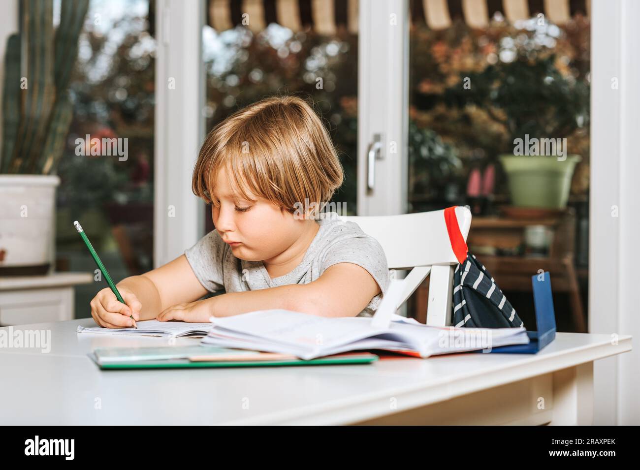 Cute little boy doing homework for school, writing in excersice ...