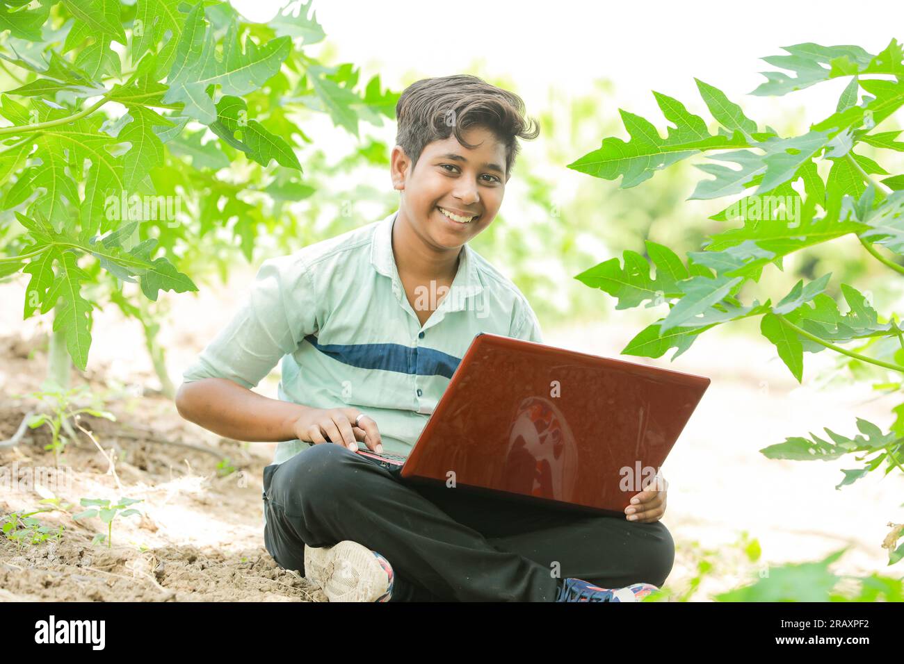 Indian boy studying in farm, holding laptop in hand , poor indian kids ...