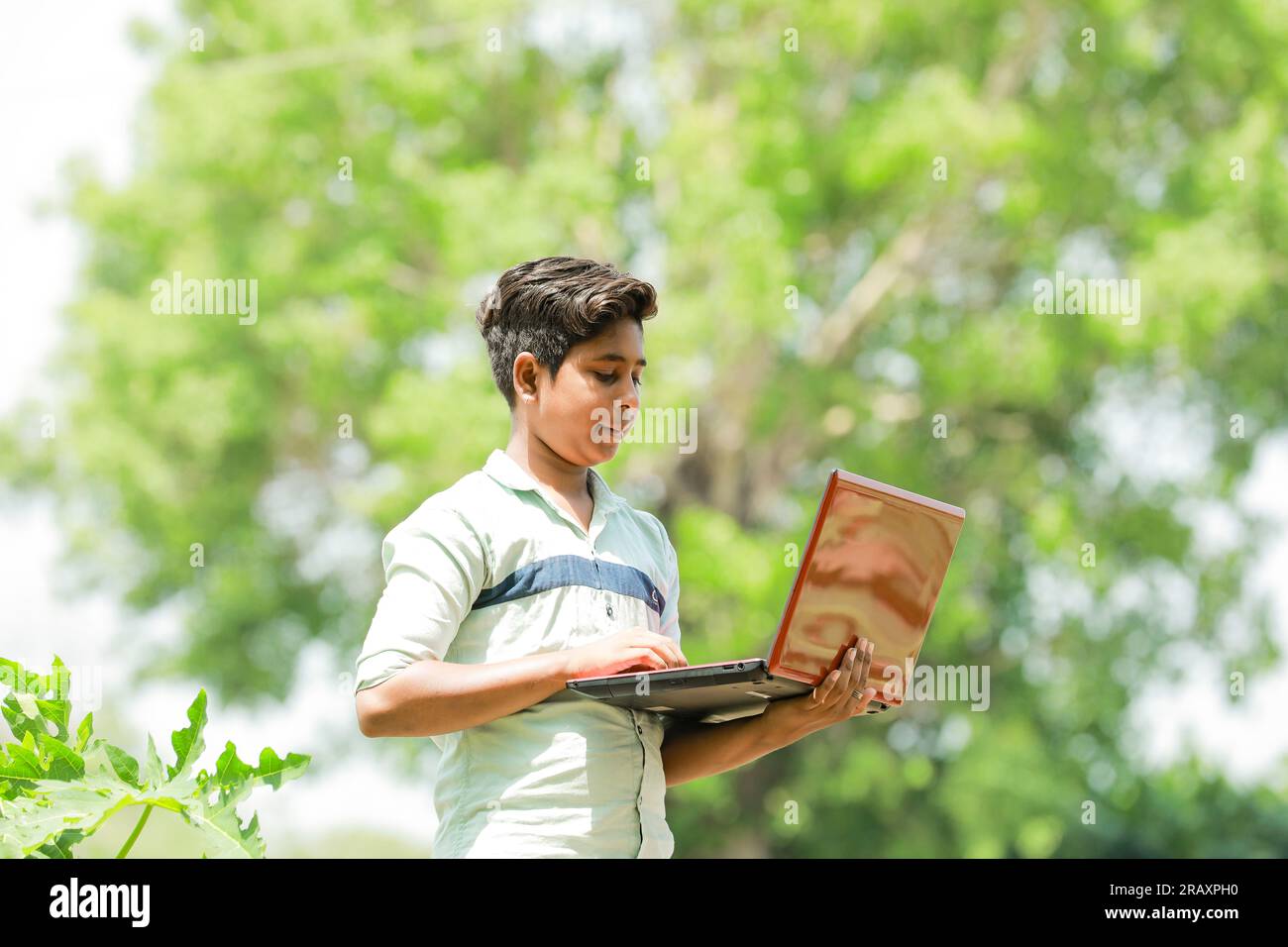 Indian boy studying in farm, holding laptop in hand , poor indian kids ...