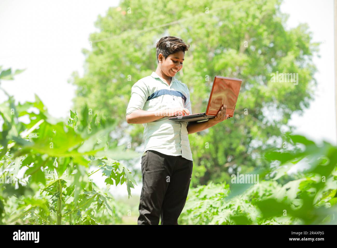 Indian boy studying in farm, holding laptop in hand , poor indian kids ...