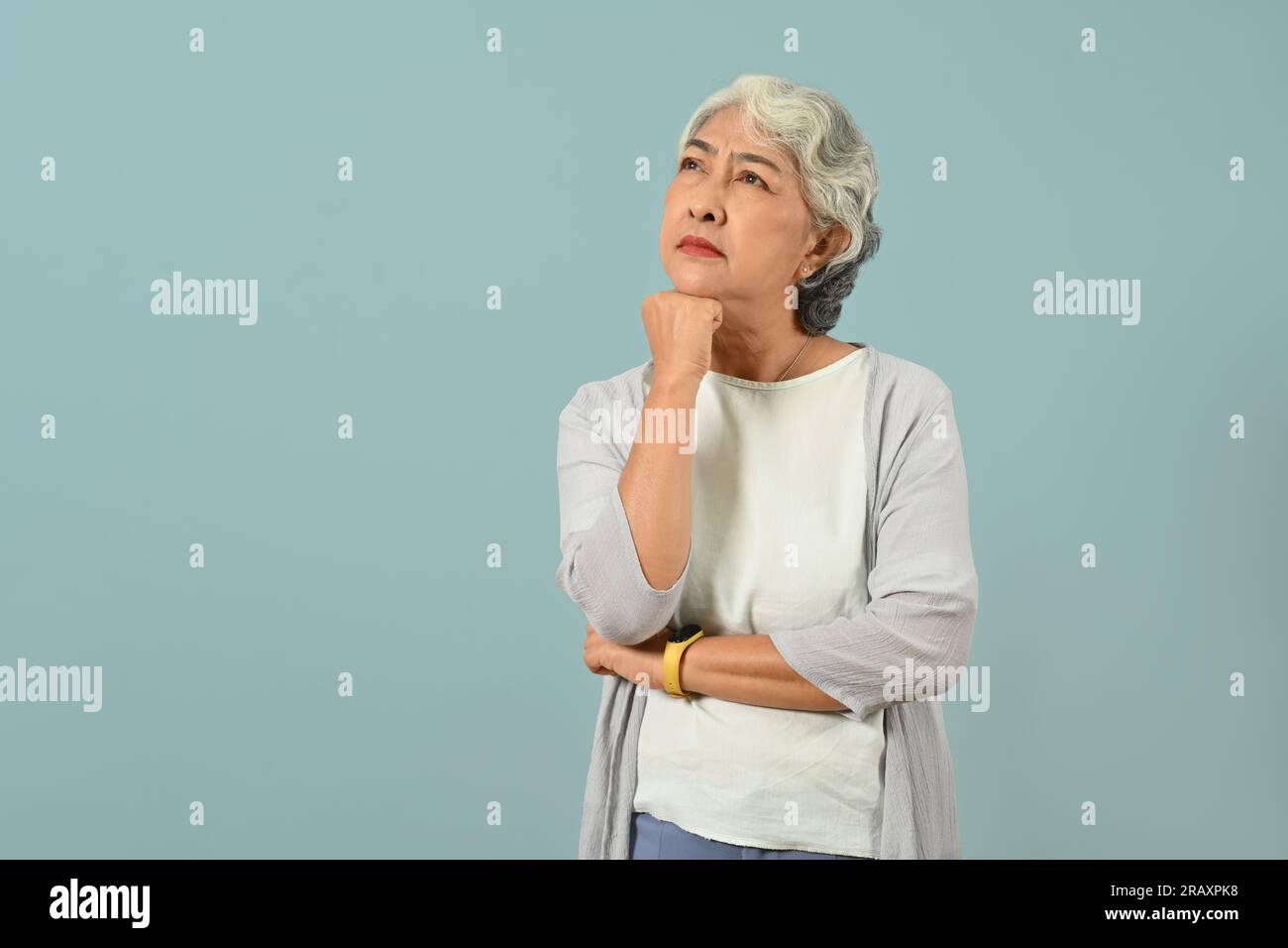 Thoughtful senior woman thinking and looking up expressing doubt and ...