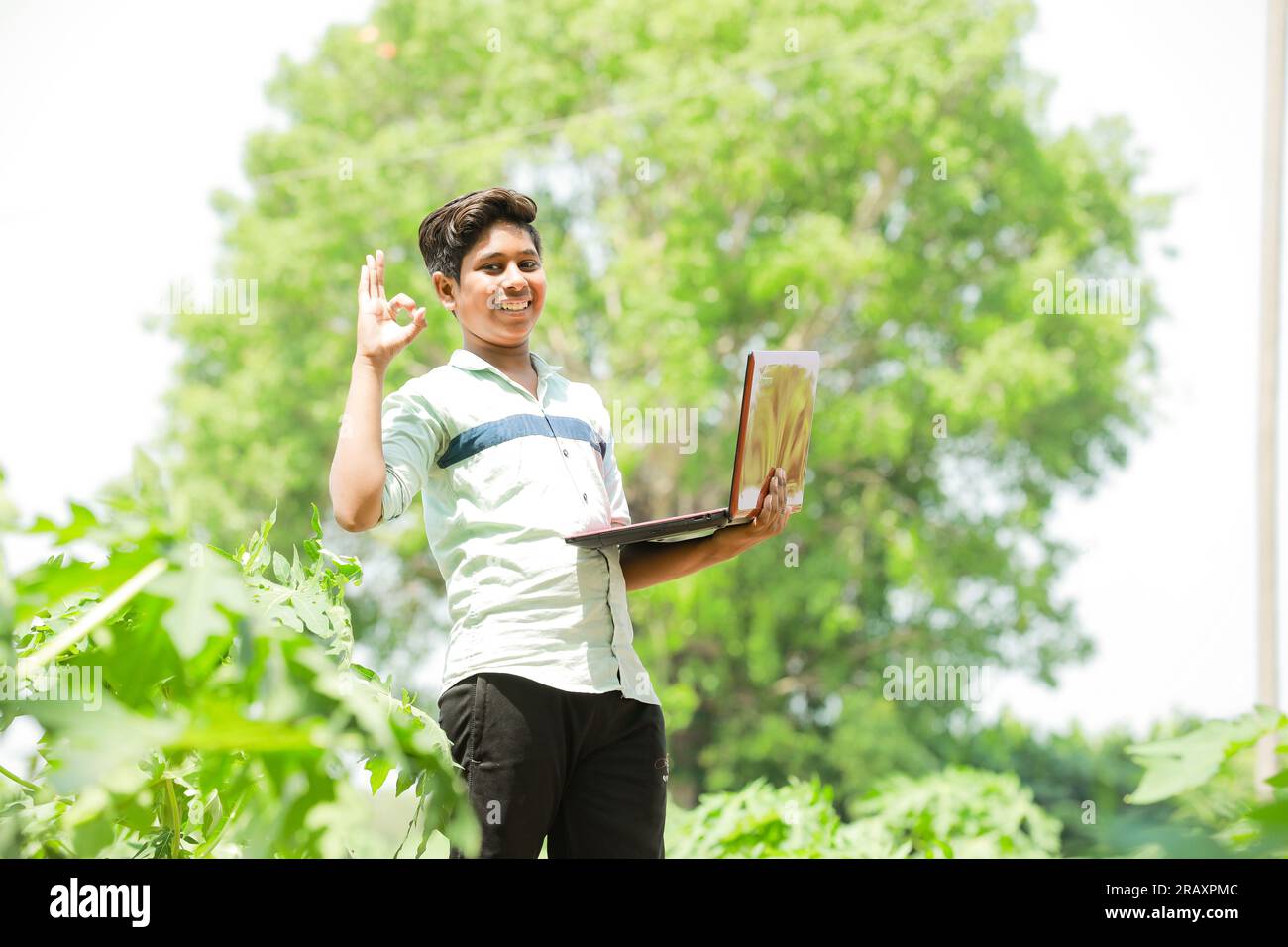 Indian boy studying in farm, holding laptop in hand , poor indian kids ...