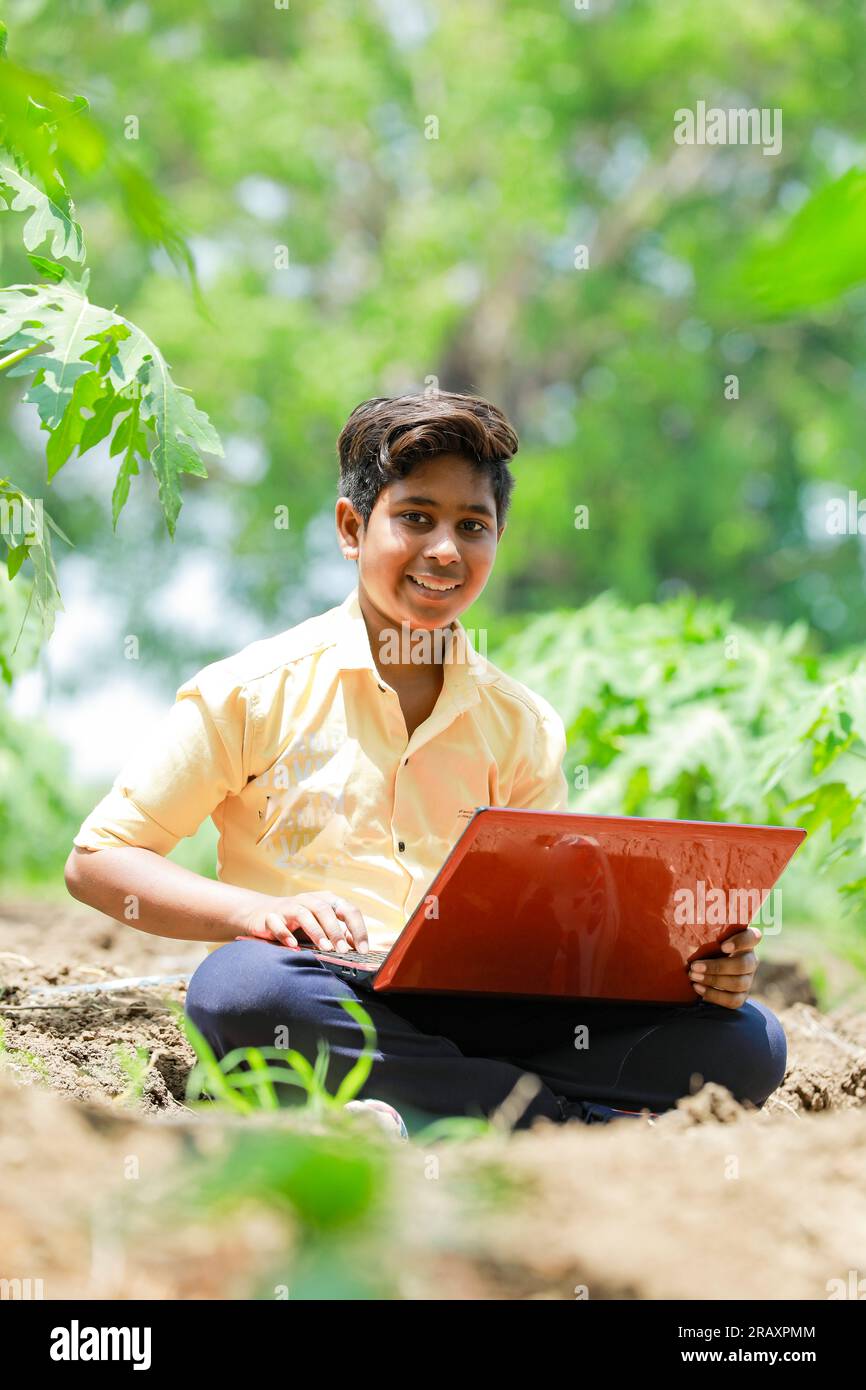 Indian boy studying in farm, holding laptop in hand , poor indian kids ...