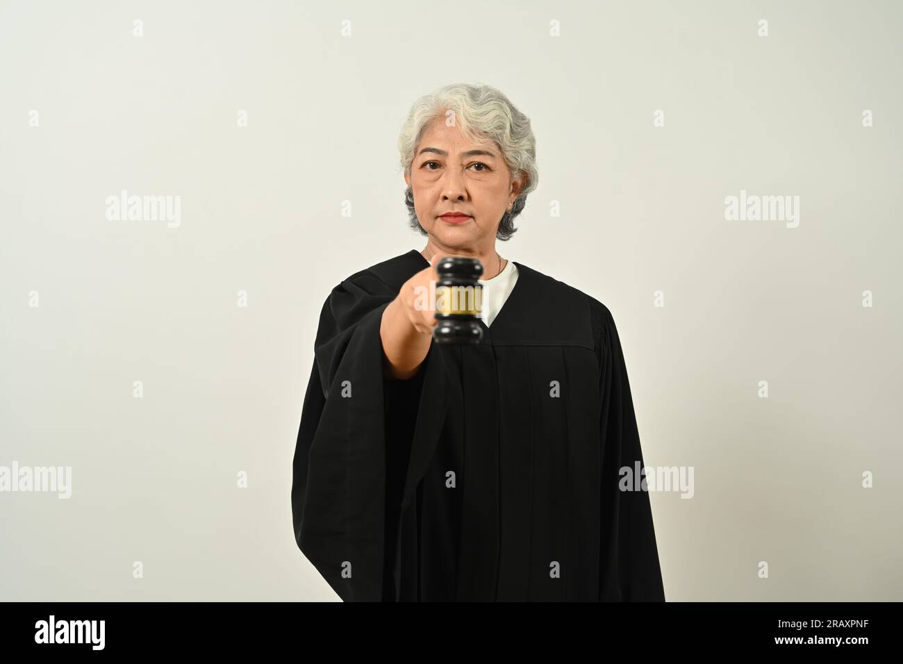 Strict senior female judge dressed in robe gown uniform with gavel ...