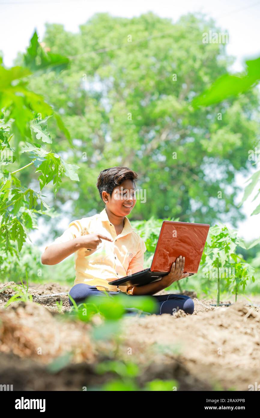 Indian boy studying in farm, holding laptop in hand , poor indian kids ...