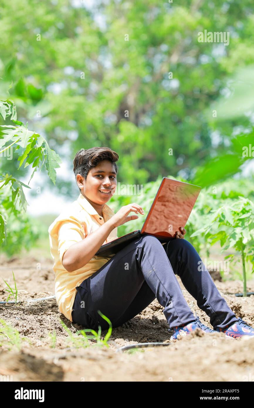 Indian boy studying in farm, holding laptop in hand , poor indian kids ...