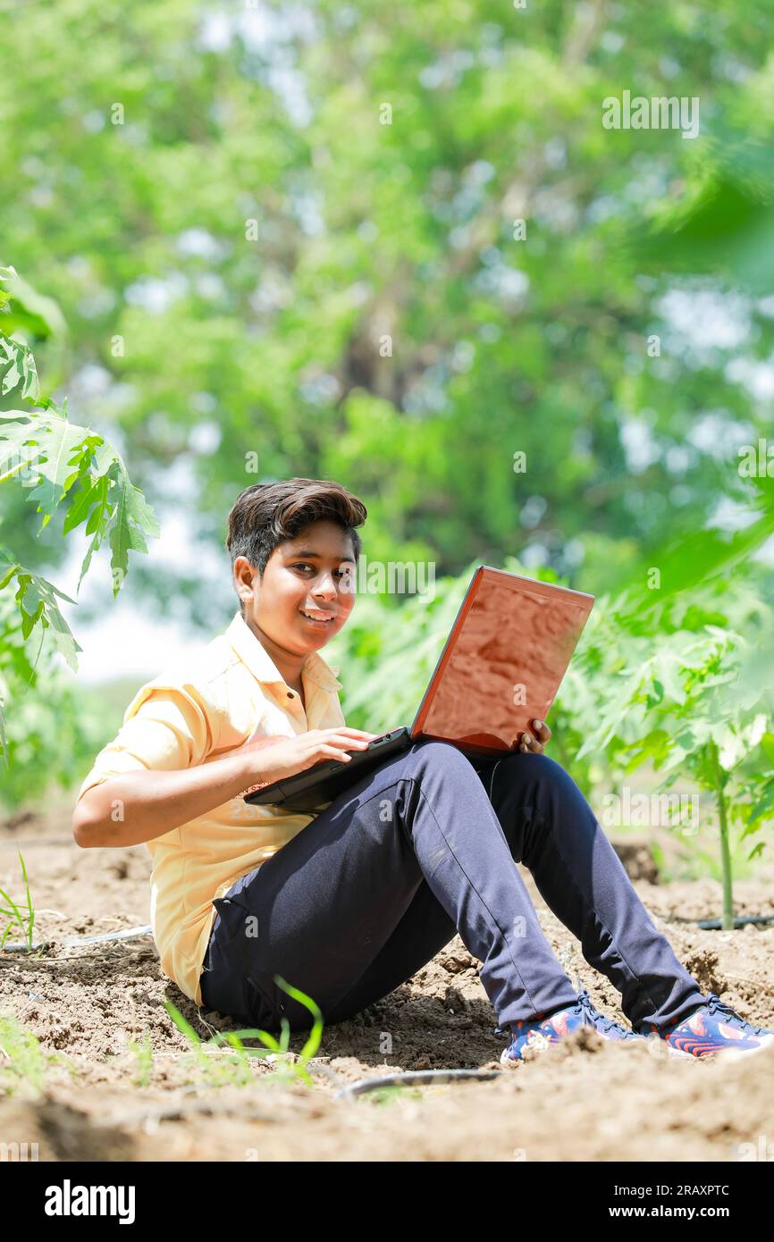 Indian boy studying in farm, holding laptop in hand , poor indian kids ...