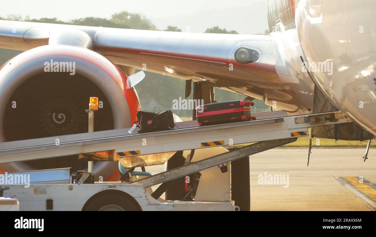 process of carrying luggage bag on a conveyor belt to airplane before ...