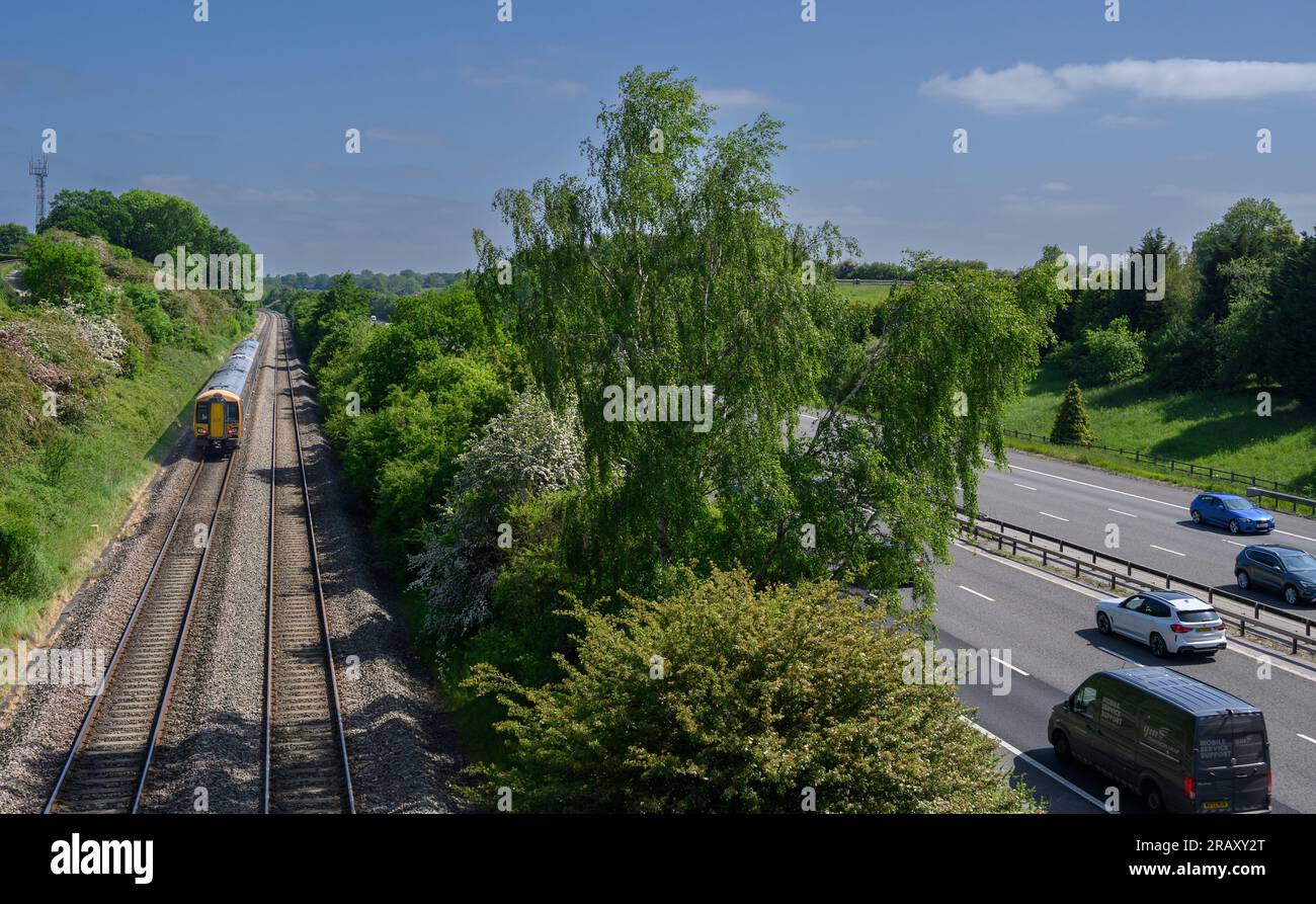 Train in West Midlands Trains livery travelling along track running parallel with the M40 ...