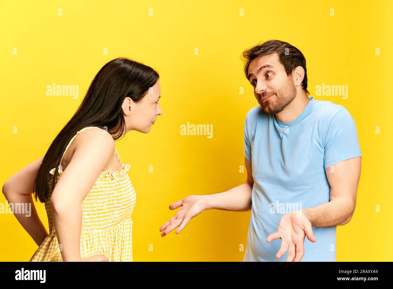 Young woman emotionally talkin to man, asking questions against yellow ...