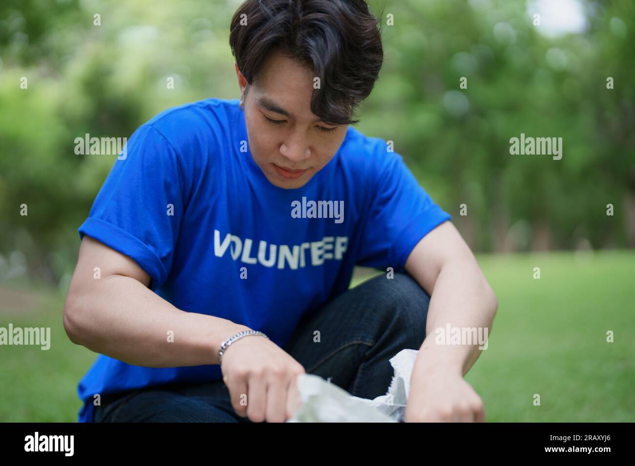 Multiethnic volunteers donate their time holding black garbage bags to ...