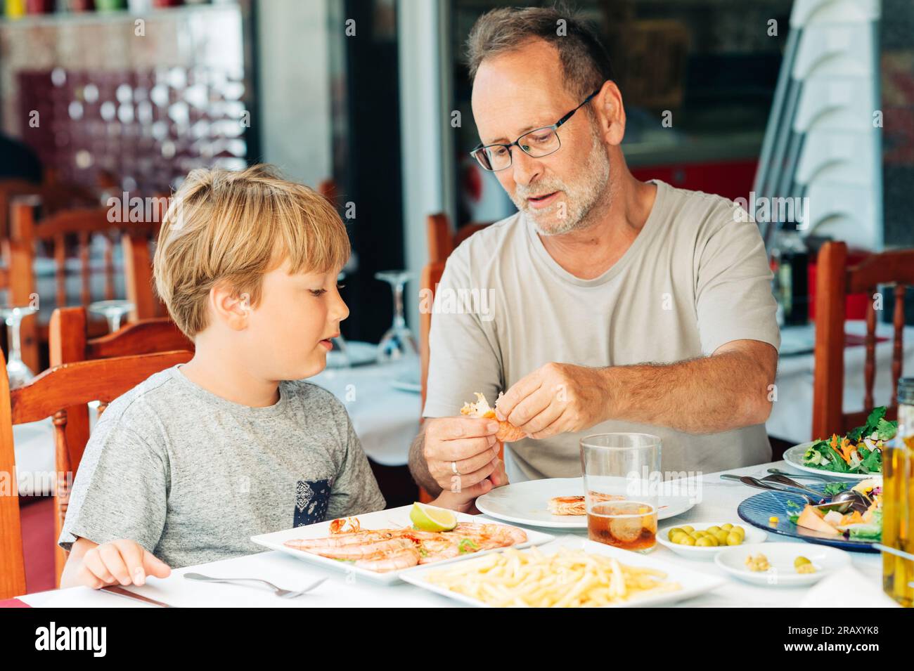 Family in the restaurant, father and sun eating shrimps, summer ...