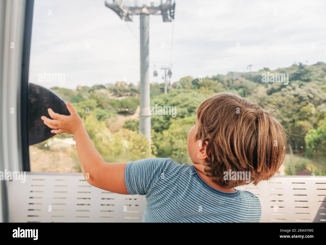 Cute little boy enjoying ride in cable car during summer vacation ...