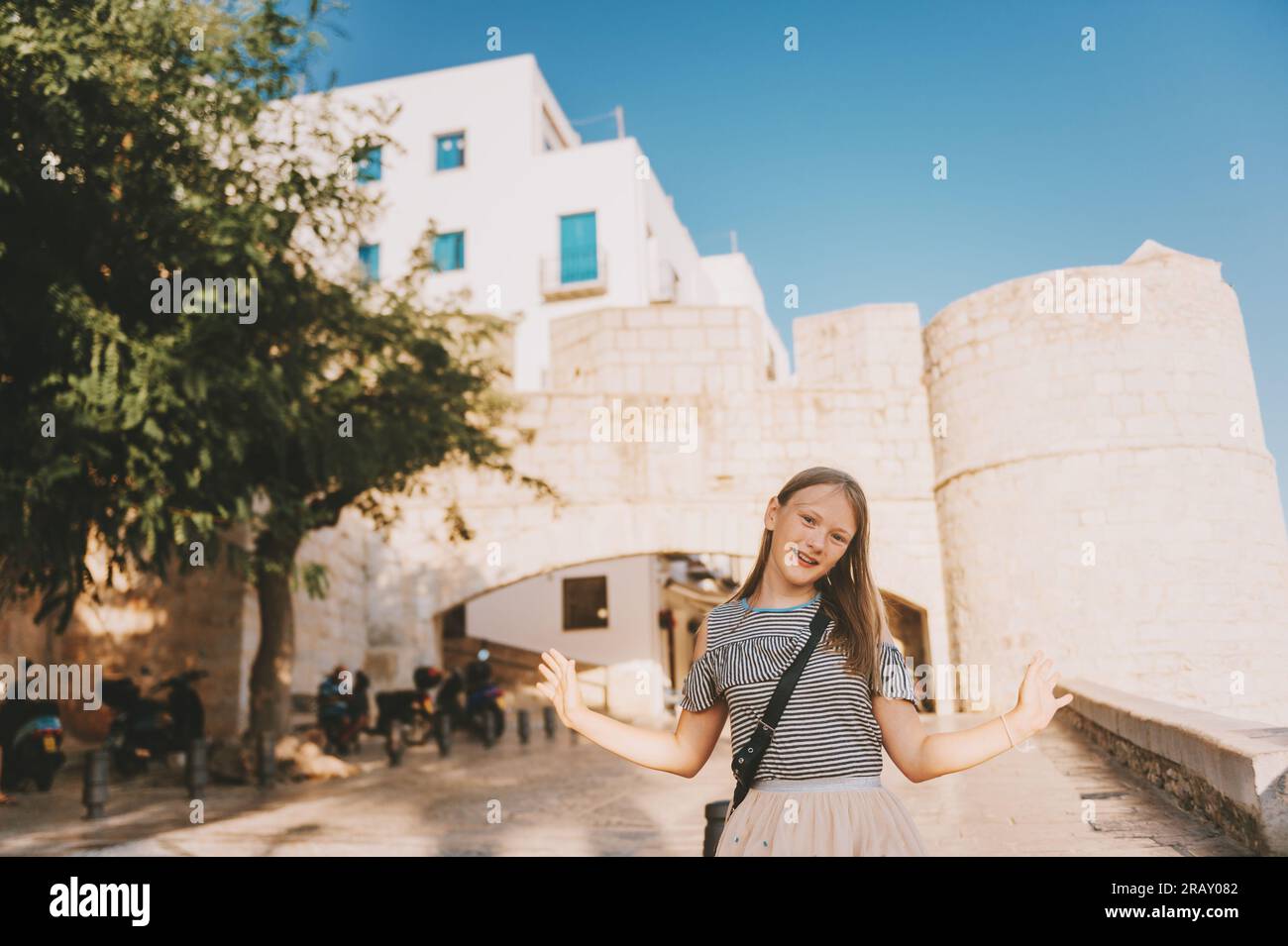 Young happy kid girl posing infront of entrance of fortified old town ...