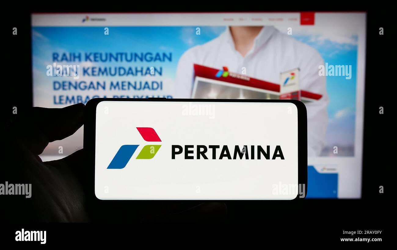 Person holding mobile phone with logo of Indonesian company PT Pertamina (Persero) on screen in ...