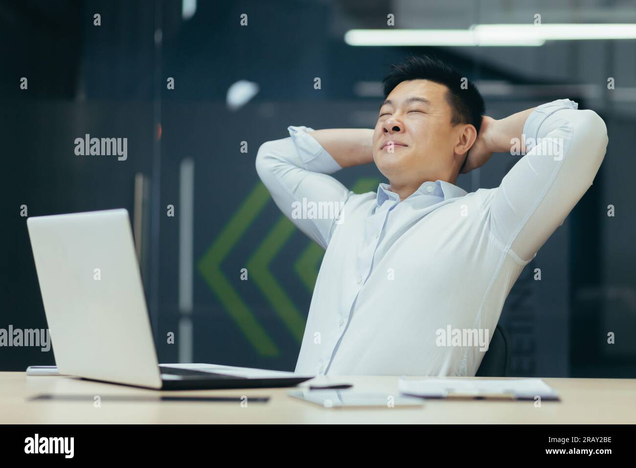 Young Asian male businessman sitting in the office at the desk and ...