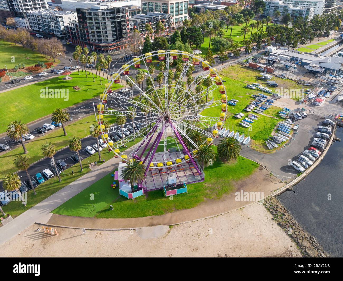 Aerial view of a ferris wheel surrounded by waterfront parkland and car ...