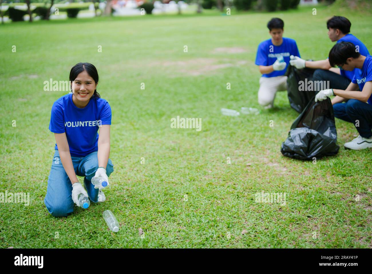 Multiethnic volunteers donate their time holding black garbage bags to ...