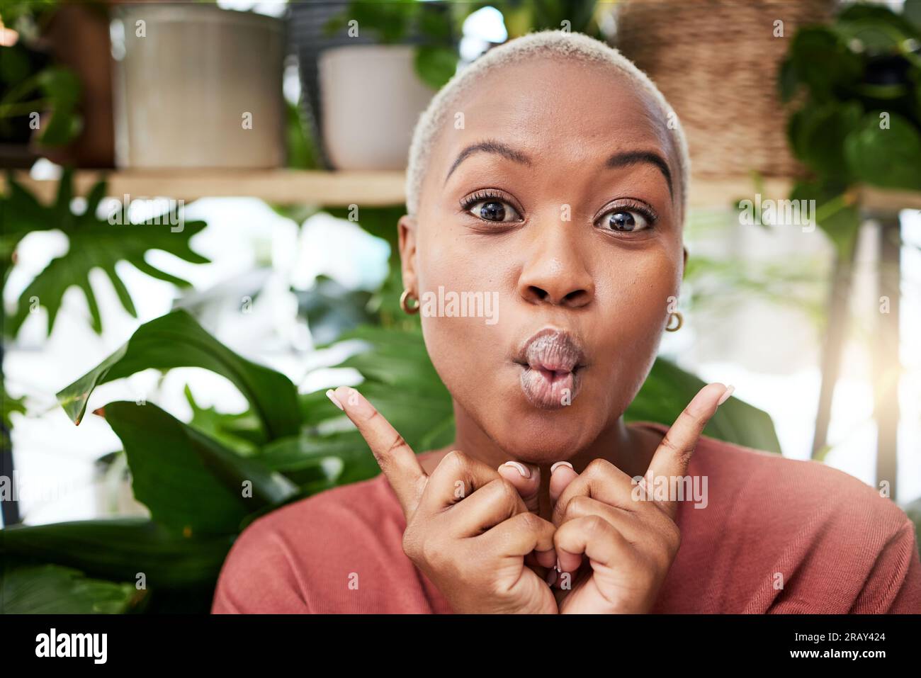 Black woman, silly face and home with comedy feeling happy with plants ...