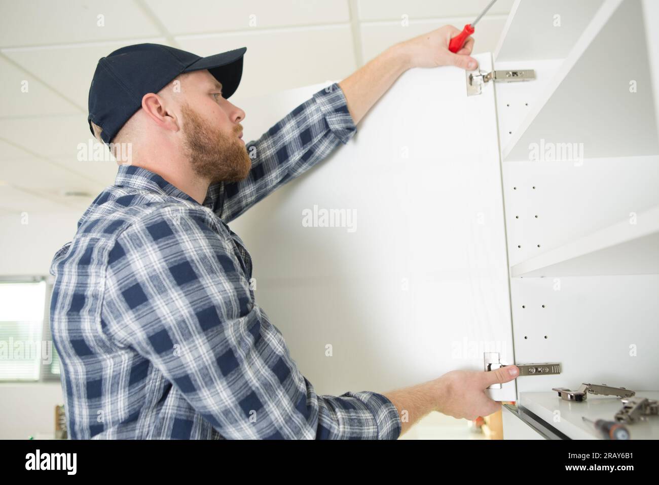 handyman fixing a door on the cupboard Stock Photo - Alamy