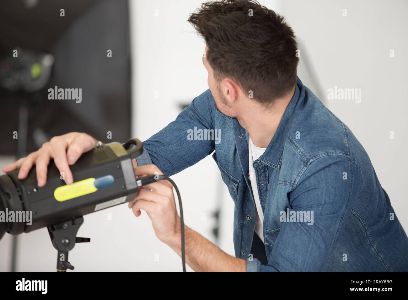 male photographer adjusting lighting during studio photoshoot Stock ...