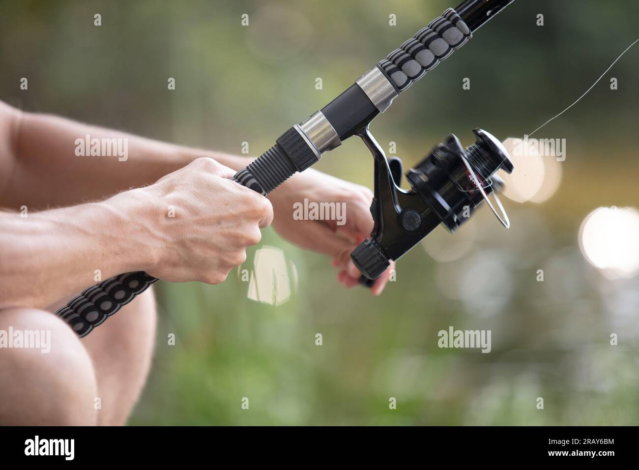 fisherman reeling in the line on his fishing rod Stock Photo - Alamy