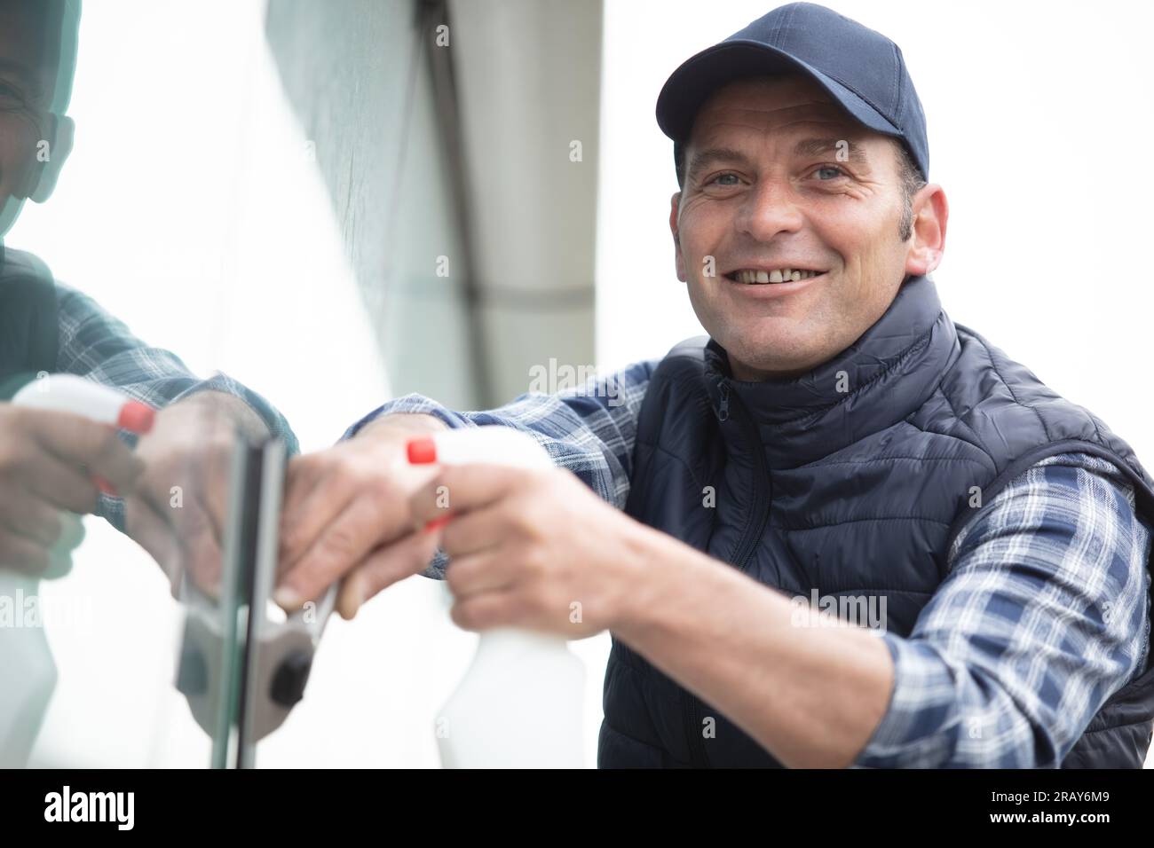 male janitor using a squeegee to clean a window Stock Photo - Alamy