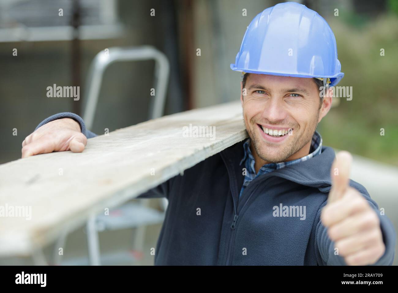 construction worker carrying a wood plank shows thumb up Stock Photo ...