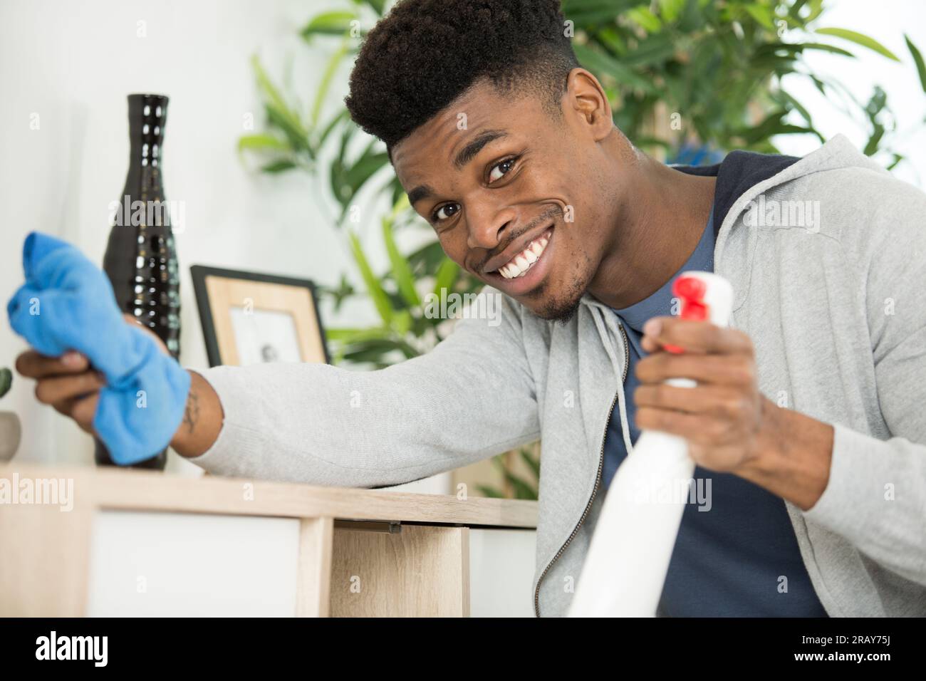 man doing housework holding cloth and spray Stock Photo - Alamy