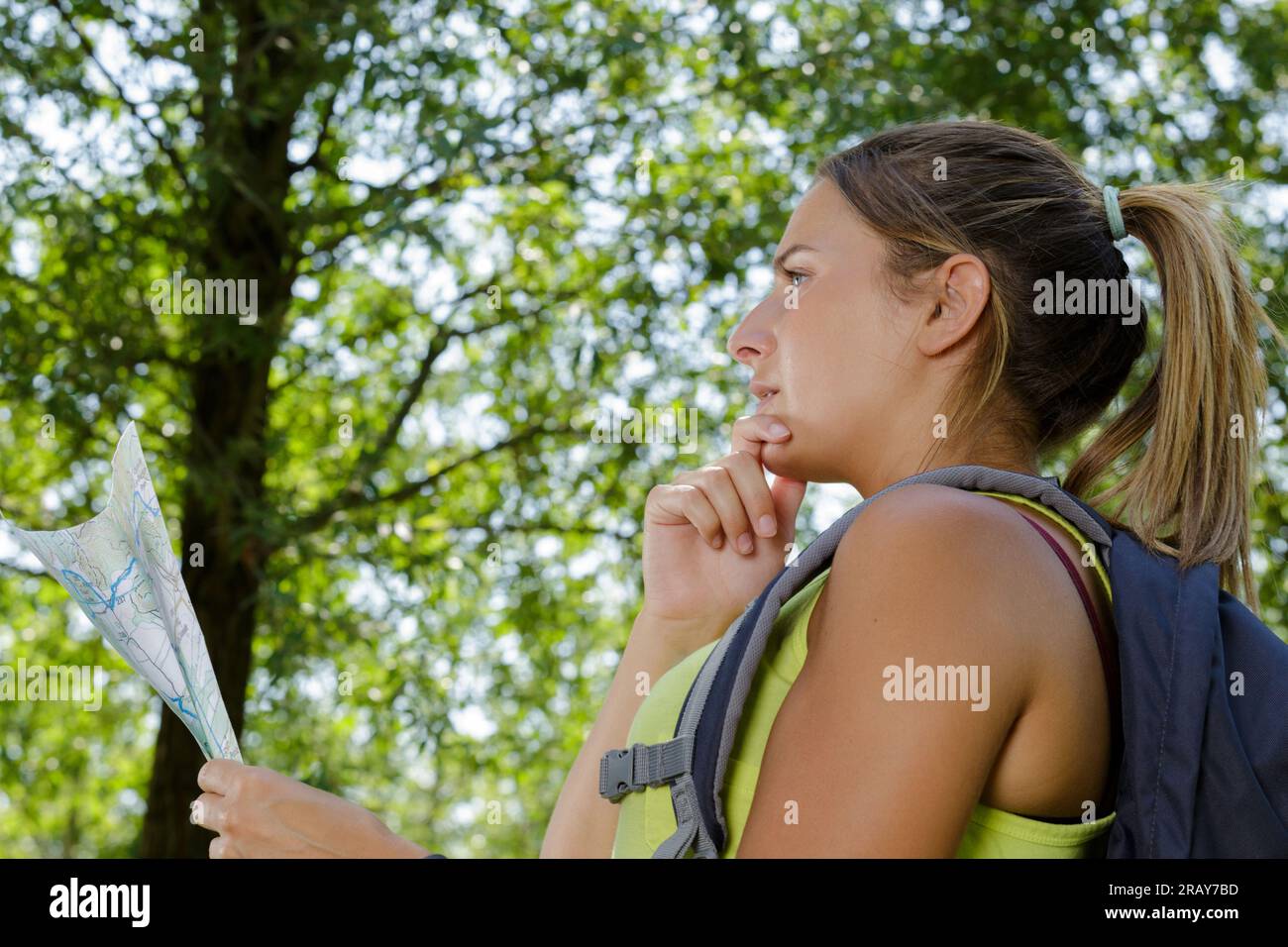 female hiker thinking where to go holding map Stock Photo - Alamy