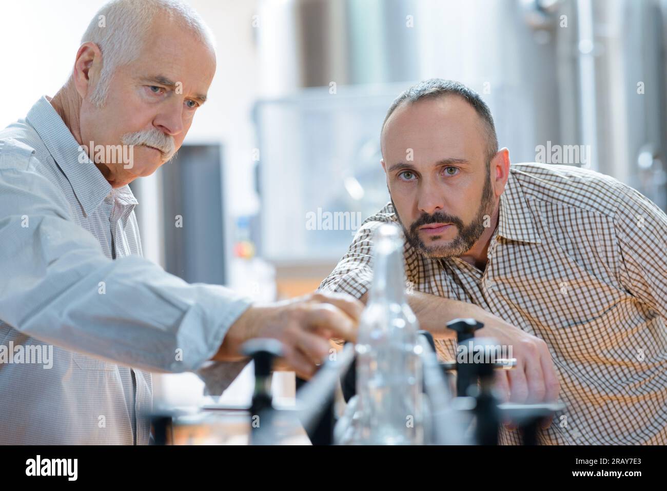 two men looking at the beaker with beer Stock Photo - Alamy