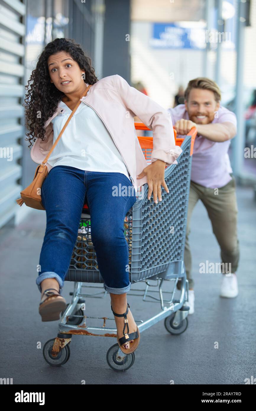 woman sitting in shopping cart while her boyfriend pushing it Stock ...