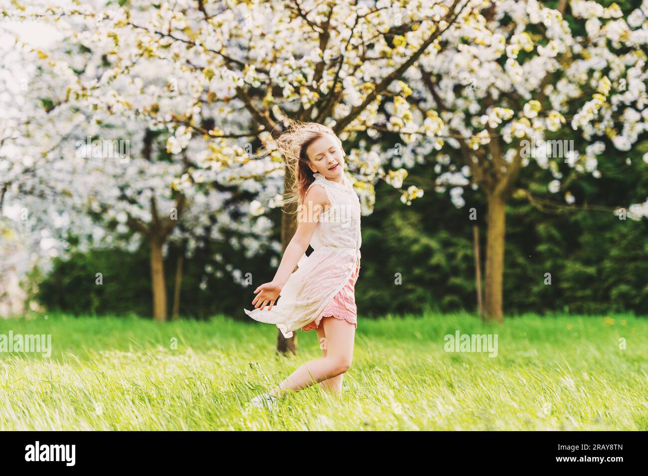 Pretty little kid girl dancing in spring blooming garden Stock Photo ...