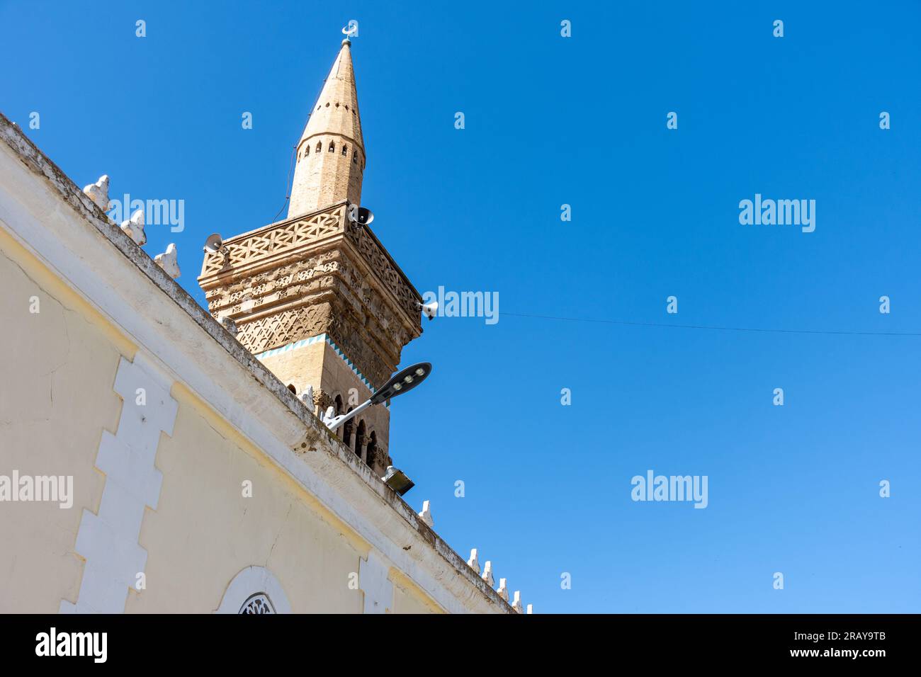 View of EL Atik mosque minaret against a blue sky in Setif city. The ...