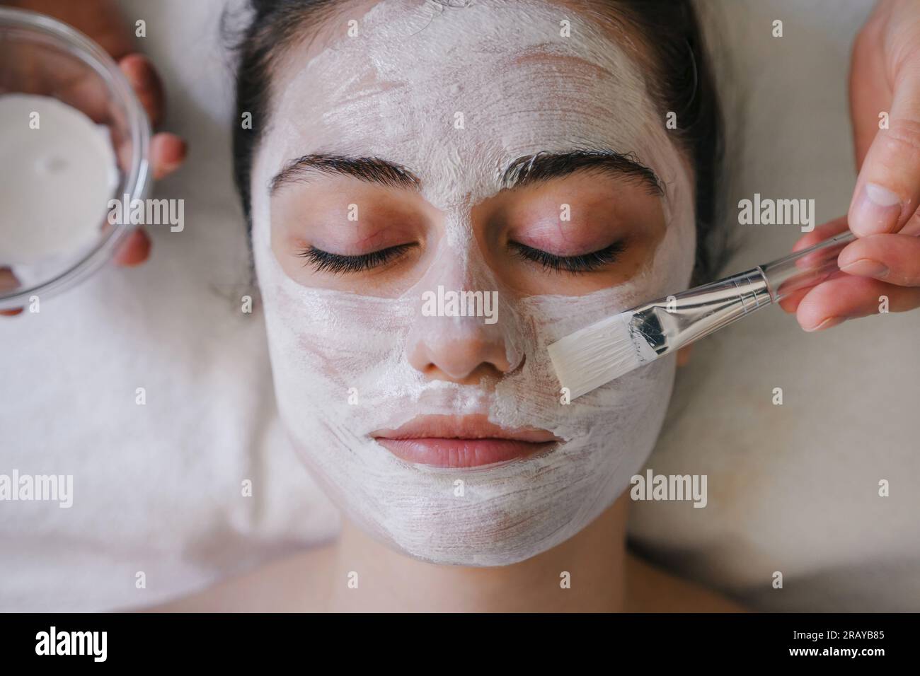 Close up portrait of a young woman having a facial white mask on her ...