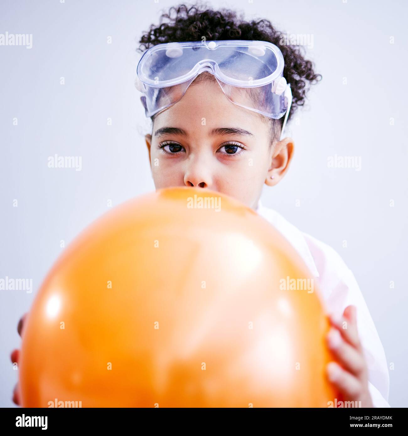 Portrait, science and a kid blowing a balloon in studio on a gray ...
