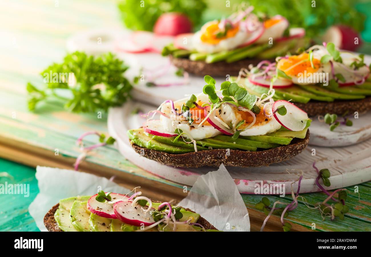 Open sandwiches with avocado,radish, boiled egg and sprouts. Concept of ...
