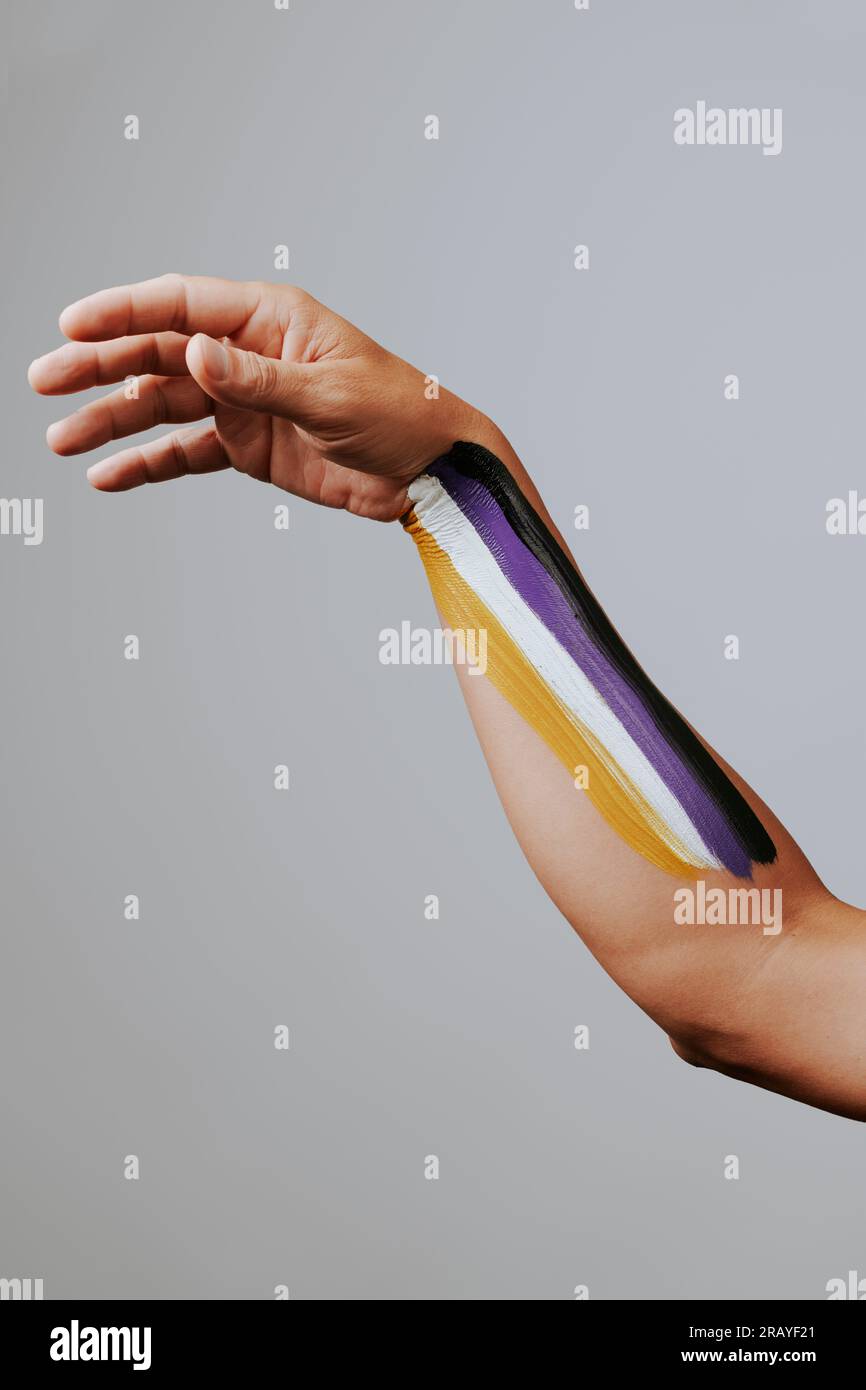 the arm of a young caucasian person with the non-binary pride flag ...