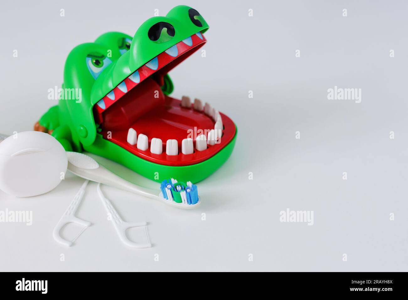 Dental floss, toothpicks, brush and green crocodile on white background ...